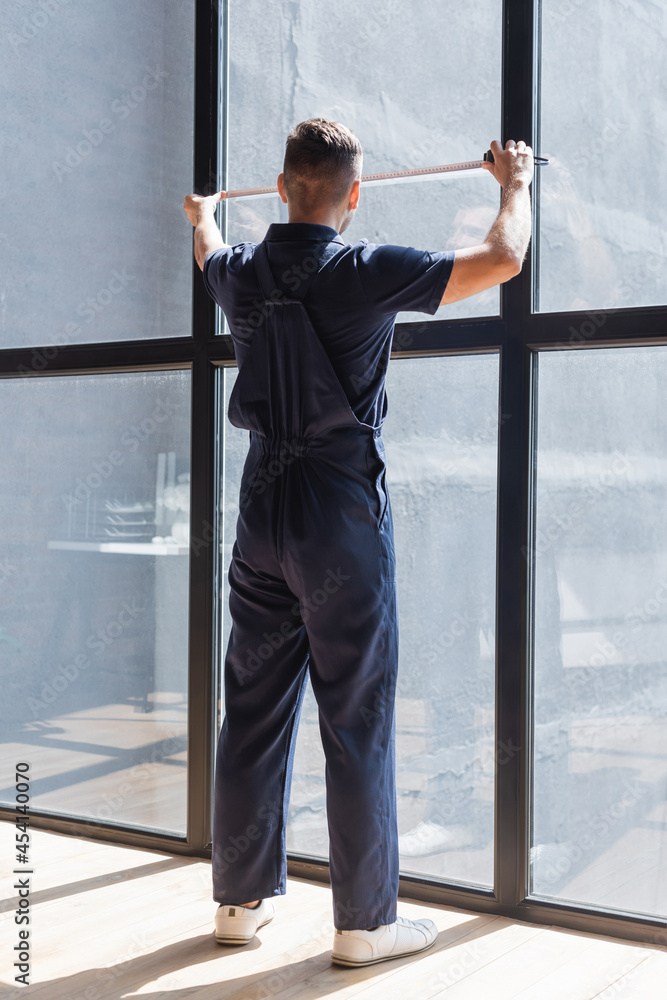 back view of workman in overalls measuring large windows Stock Photo ...
