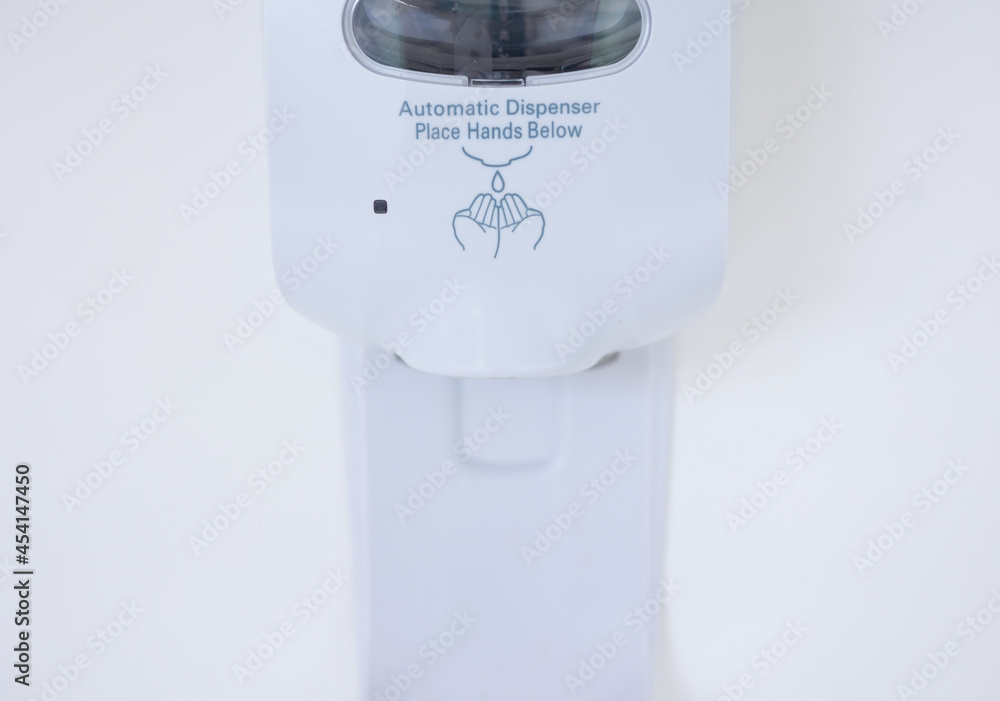 Close up and front view of automatic alcohol gel dispenser mounted on ...