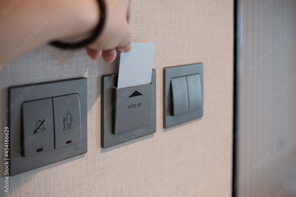 Hand inserting a key card in a hotel room. Stock Photo | Adobe Stock
