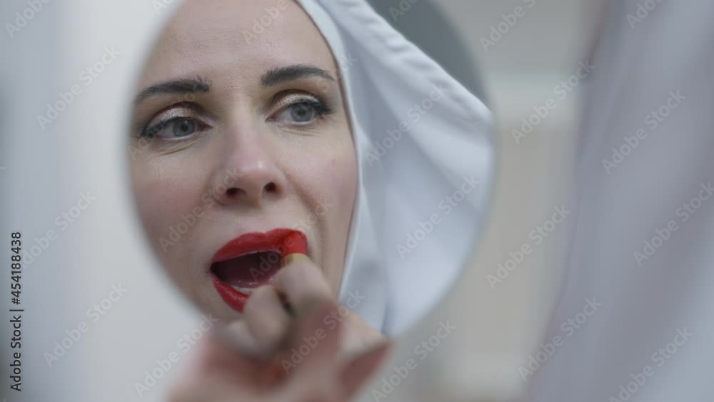 Close-up reflection in hand mirror of slim gorgeous woman in nun ...