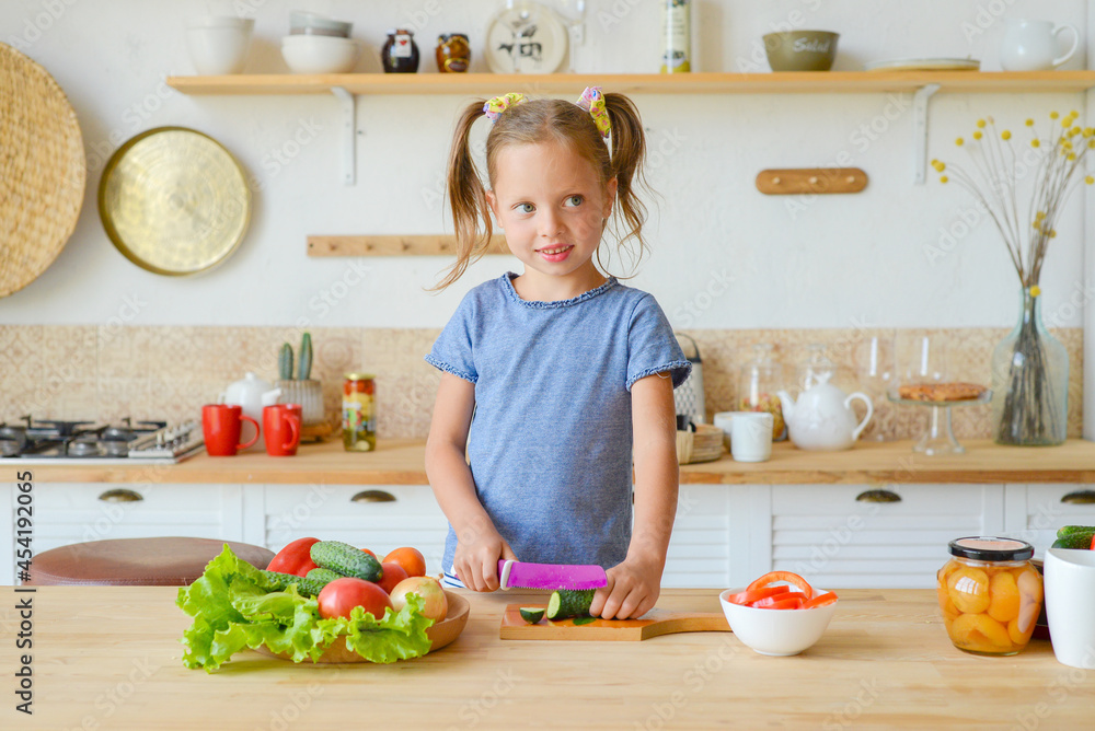 Adorable child is cooking in the kitchen. Pretty pretty girl prepares ...