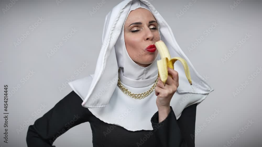 Tempting Caucasian woman in nun costume eating banana smiling looking ...