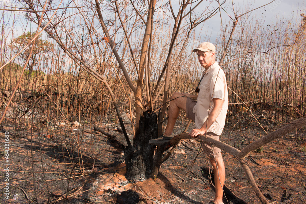 Man from the environment inspecting the remains of a brush fire at an ...