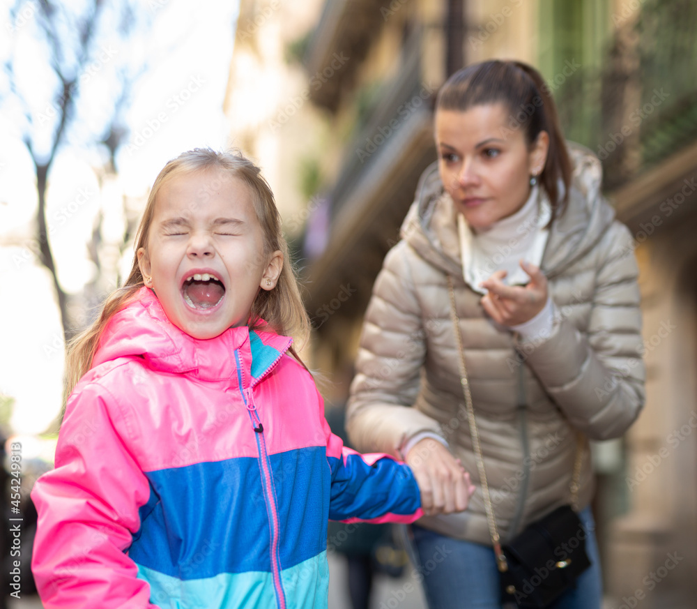 Shocked young babysitter comforting crying little girl outdoor on walk ...