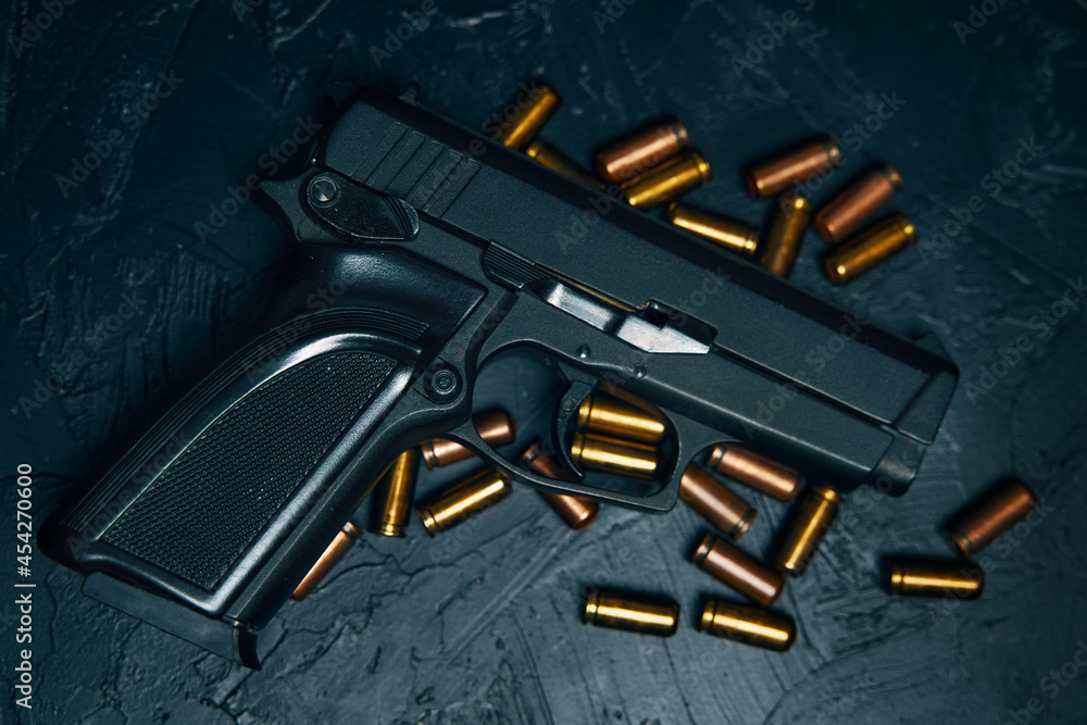 Automatic firearms with bullets. Black pistol with cartridges on table ...