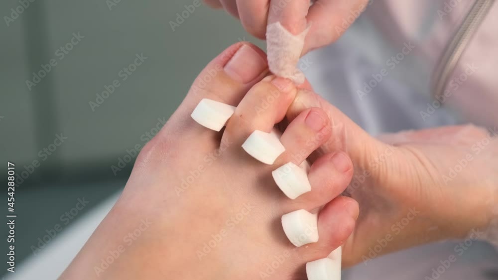 Pedicurist master is wiping woman's nails on toes using wipe in ...