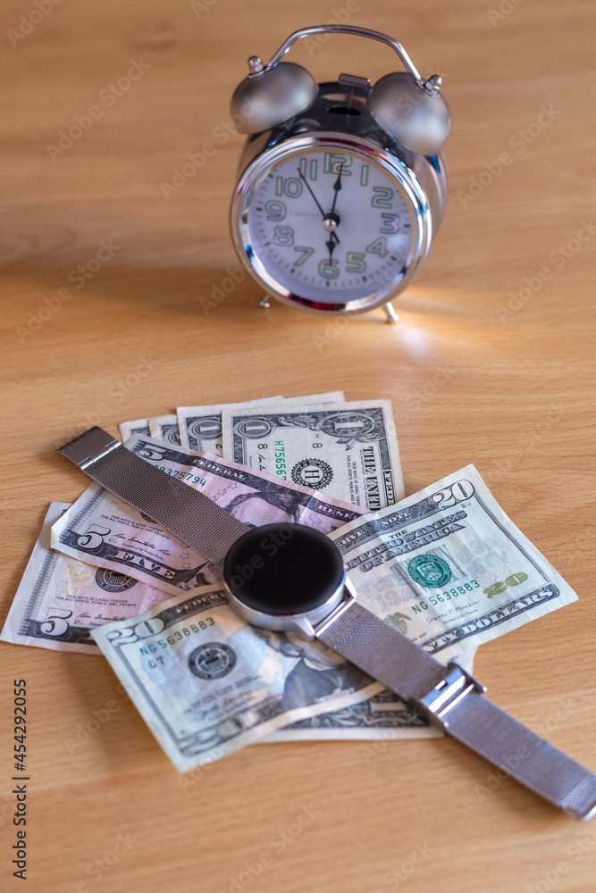 dollar money placed on a table with an analog clock and a digital clock ...