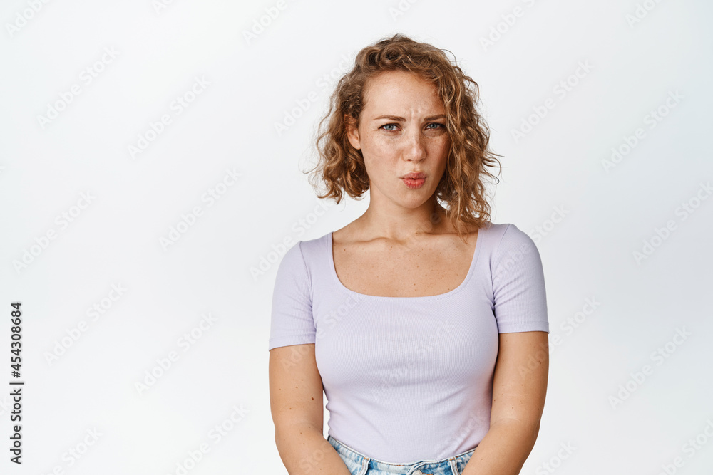Image of blond girl cringe, looking with aversion and pity at something ...