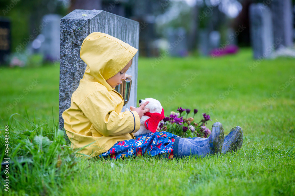Sad little child, blond boy, standing in the rain on cemetery, sad ...
