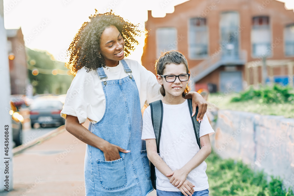Young school teacher tutor hugs autism boy while walking back to school ...
