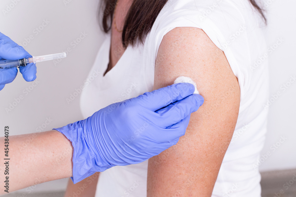 Female doctor or nurse giving shot or vaccine to patient's shoulder ...