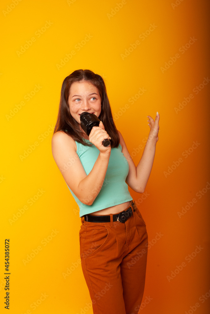 girl brunette teenager, 15 years holding a microphone in his hands ...