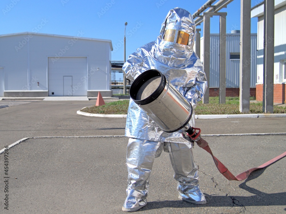 A firefighter in a shiny heat-reflecting suit and a fireman's barrel in ...