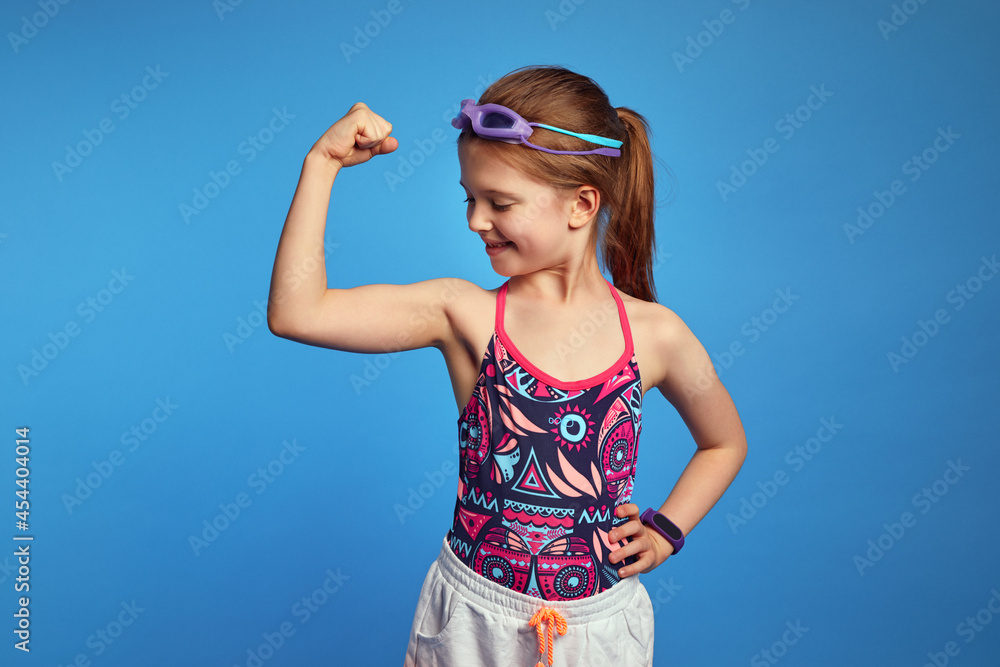 Strong kid girl spends raises arm and looking at muscles, ready for ...