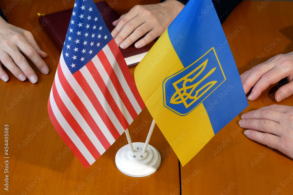 National flags of USA and Ukraine on table and hands of heads of ...