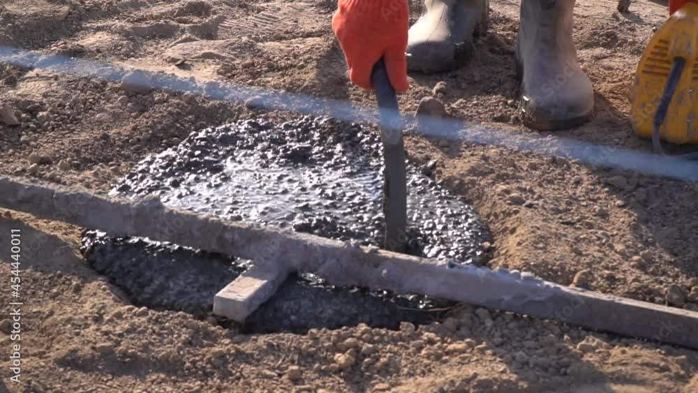 Worker is measuring the depth of fresh concrete poured into a hole ...
