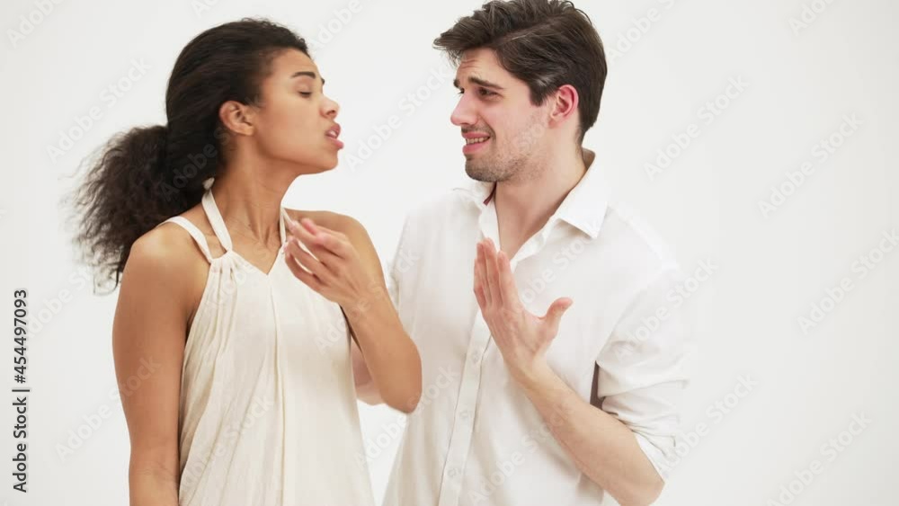 An emotional woman swearing to the camera while a man trying to calm ...