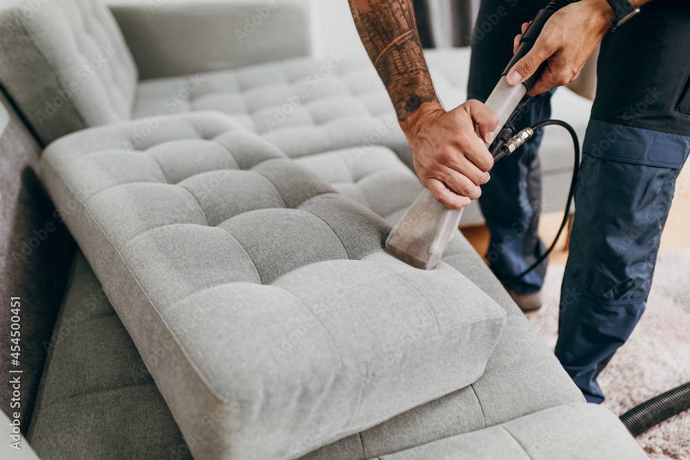 Handsome young man cleaning furniture. Process of deep furniture ...