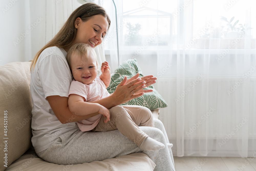 Horizontal of smiling mom clapping and looking at happy baby girl ...