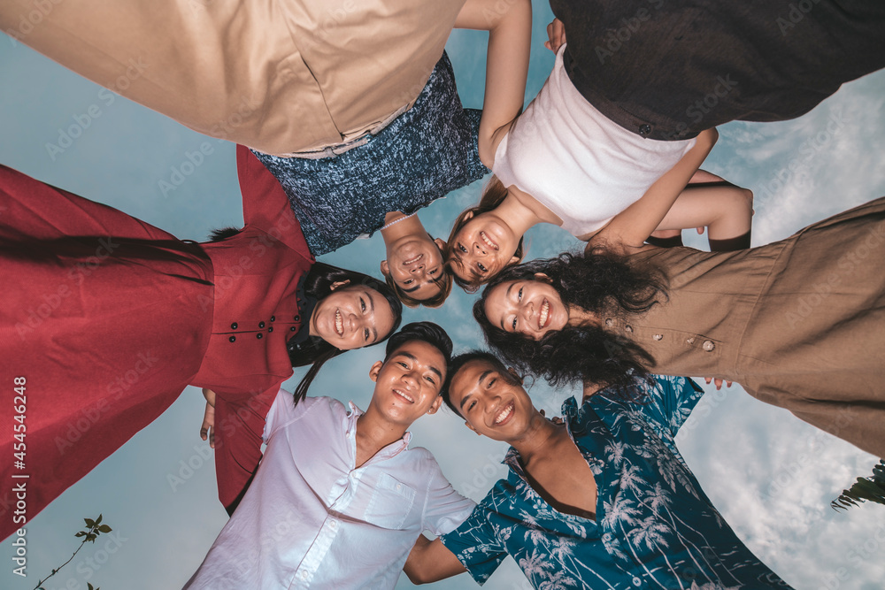 A circle of six young friends posing happily for the camera. Shot from ...