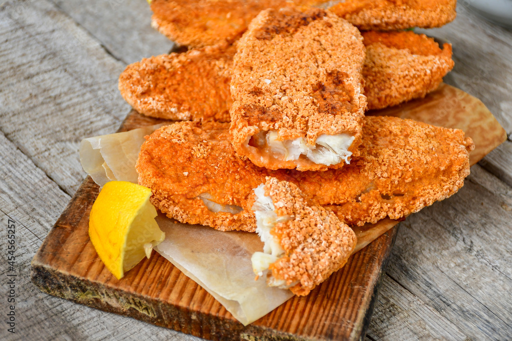 Fish and chips.Crispy breaded fish fillets and French fries on woodn ...