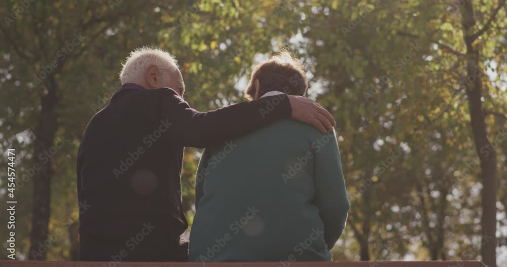 4k Back view of happy lovely caucasian senior couple sitting in bench ...