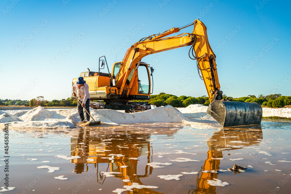 Sea salt harvest with yellow digger at salines in Faro, Portugal Stock ...