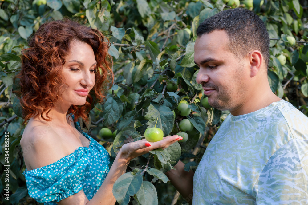 Attractive woman holding an apple on palm and offers it to man of ...