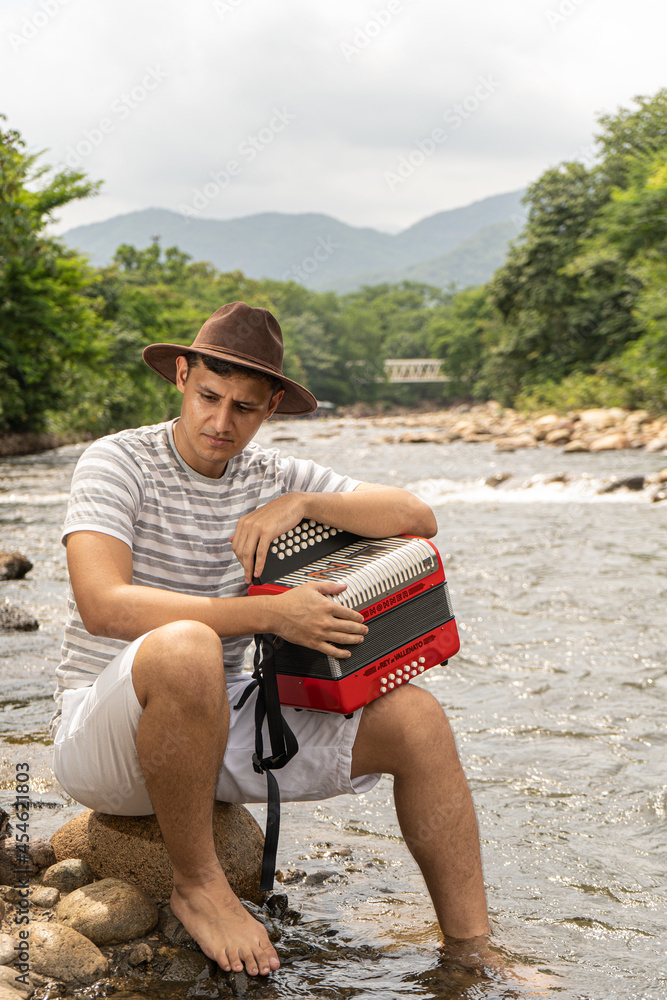 joven tocando el acordeón a orillas del rio, musico con sombrero Stock ...