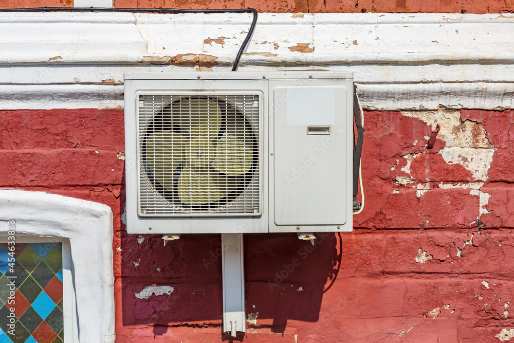 External box of an old air conditioner with a fan on the stone wall of ...