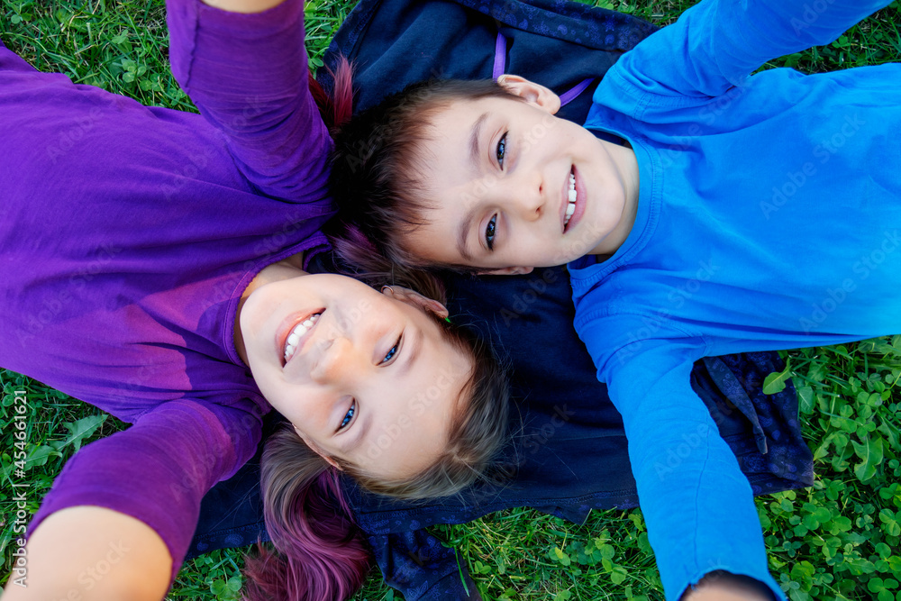 Children, a boy and a girl, lie with their backs on the green grass ...