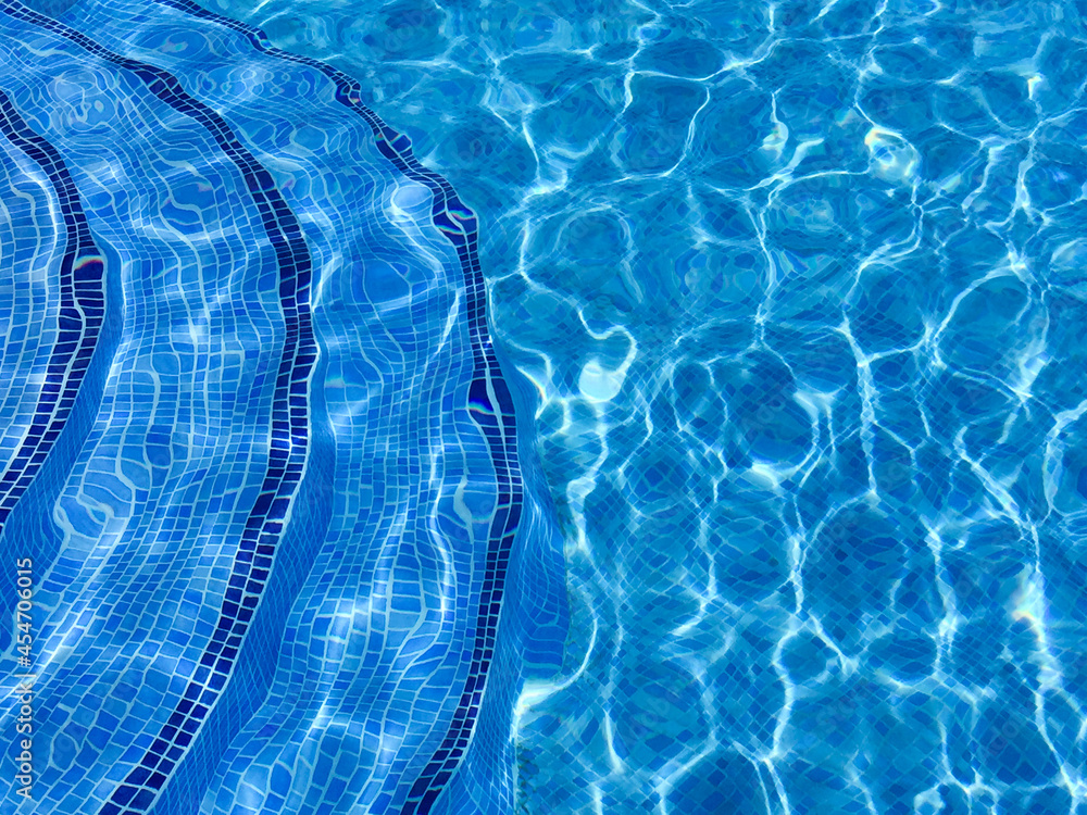 Curved steps into swimming pool, view from above through water on blue ...