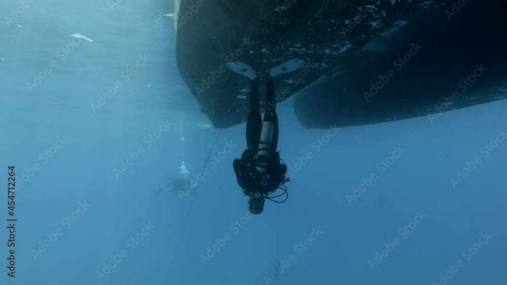 Scuba diver standing upside down on the bottom of the dive boat ...