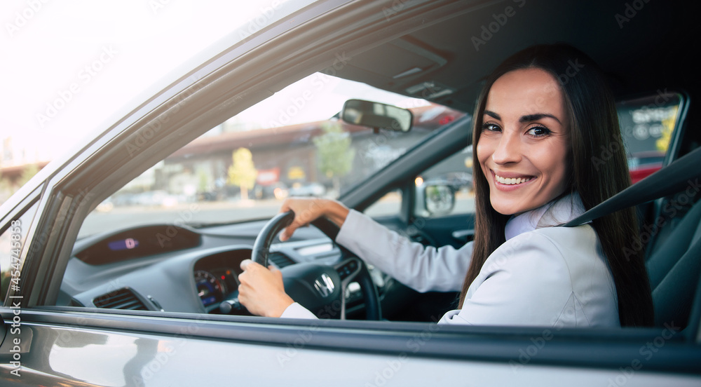 Beautiful happy successful businesswoman is driving a new modern car in ...