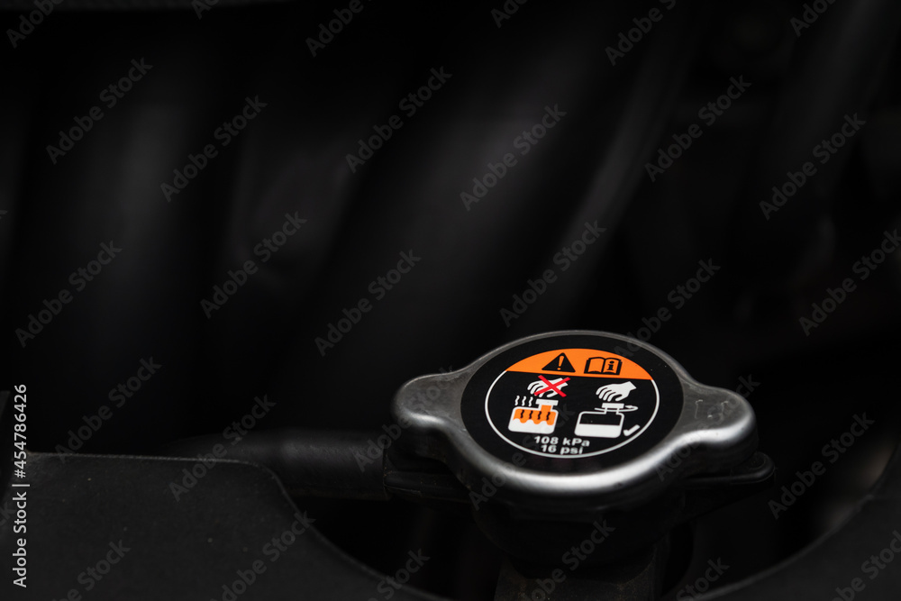 the metal cover of a radiator cap with a warning label in a car engine ...