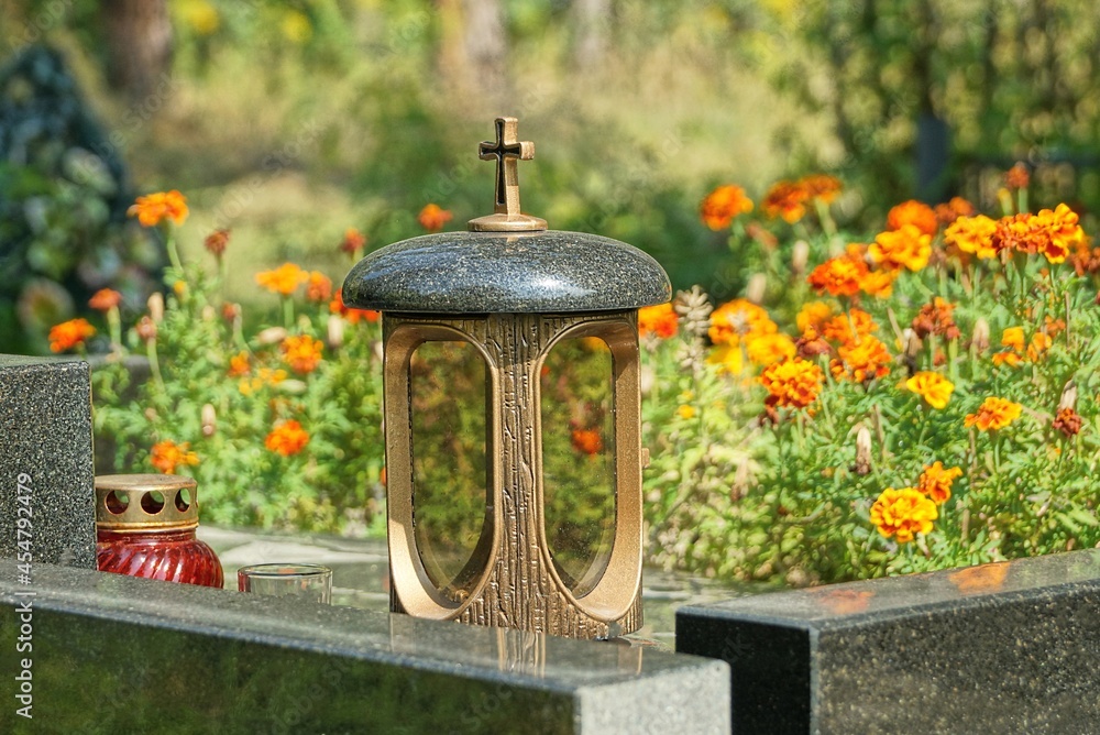 one big lamp with a cross stands on a black marble slab of a grave in a ...