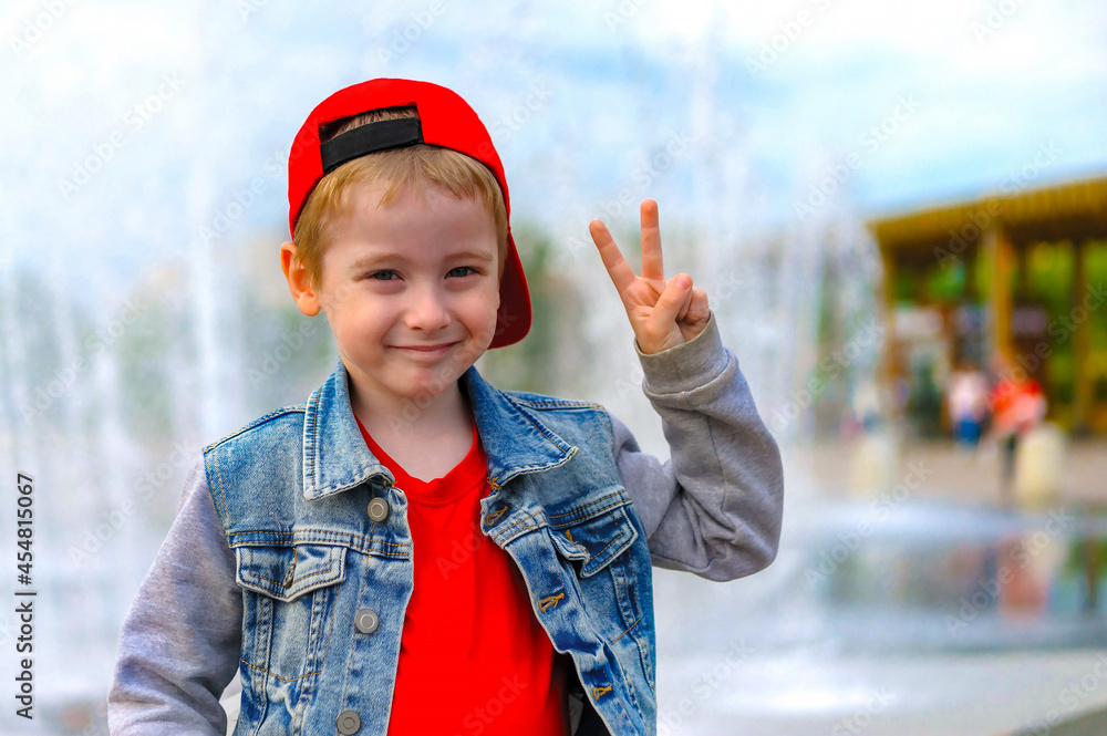 European little boy in a red cap and blue denim jacket with a happy ...