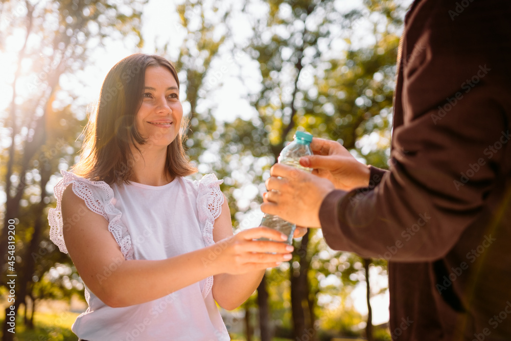 Smart pretty young woman in white blouse giving a bottle of water to a ...