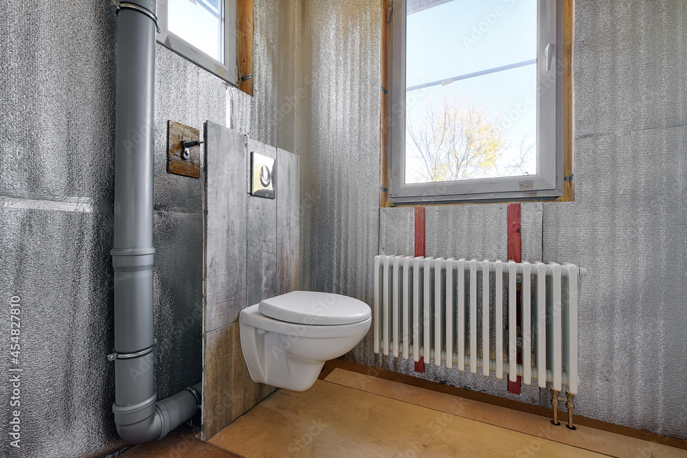 Metal heating radiator and wall-hung toilet in a country house under ...