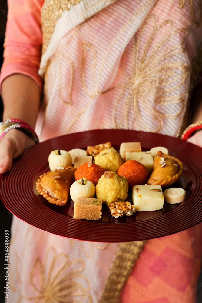 Fotografia do Stock: Indian woman serve Diwali sweets Gujiya peda barfi ...