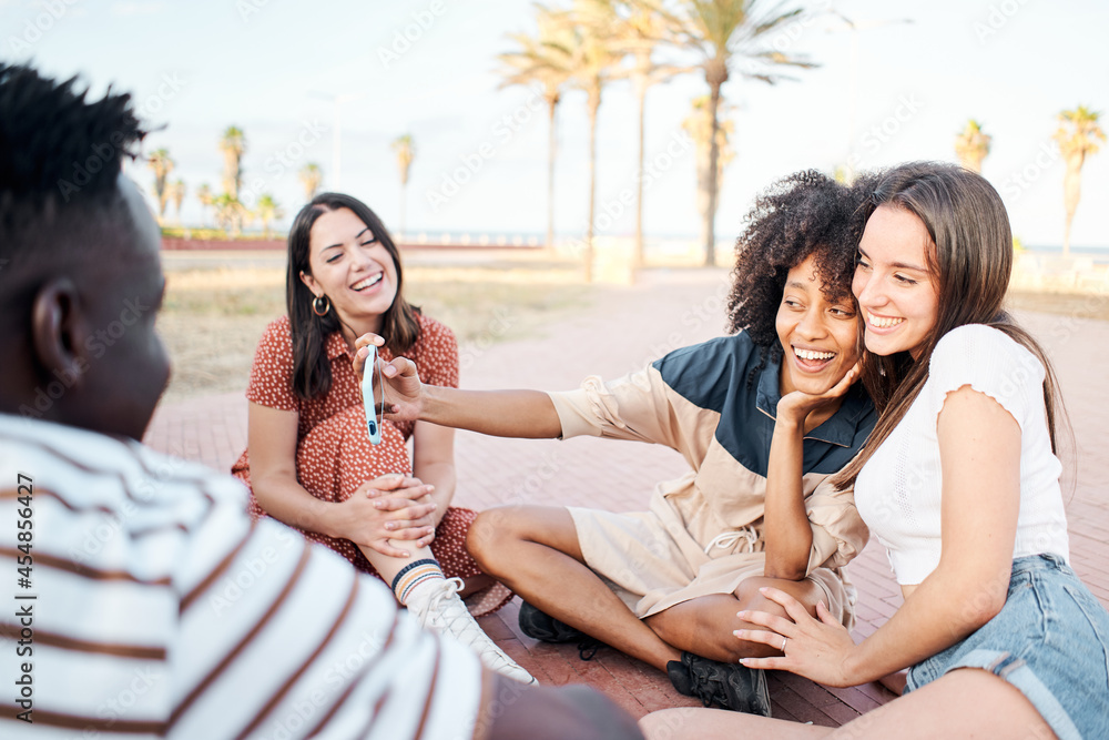 In a group of young people two girls of different races take a selfie ...
