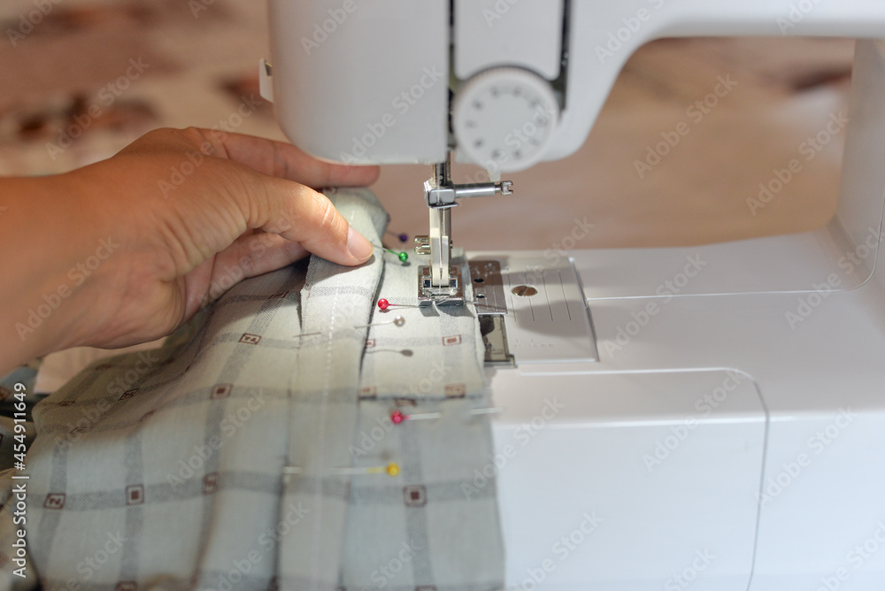 stitching on a sewing machine through tailor's needles, a dressmaker at ...