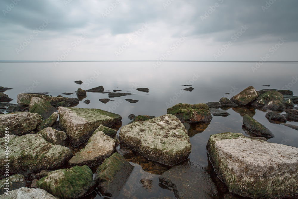 Rocks and stones covered with green algae. Smooth clear water. Stock ...