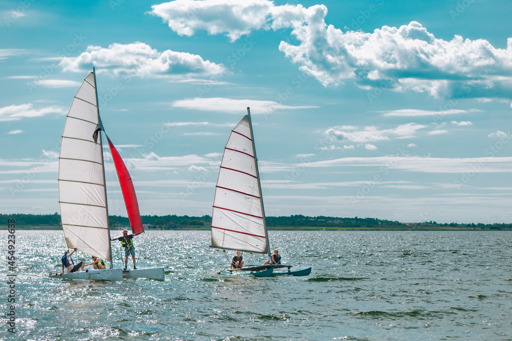 Drone photo of beautiful catamaran yacht going upwind on a lake under a ...