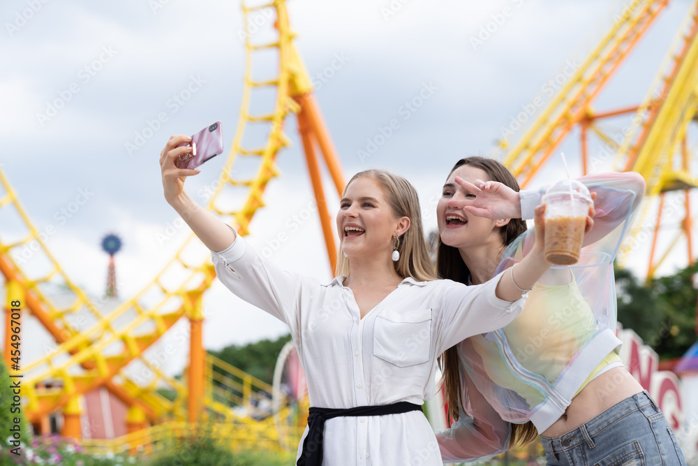 Two young female tourists at the amusement theme park on Roller coaster ...