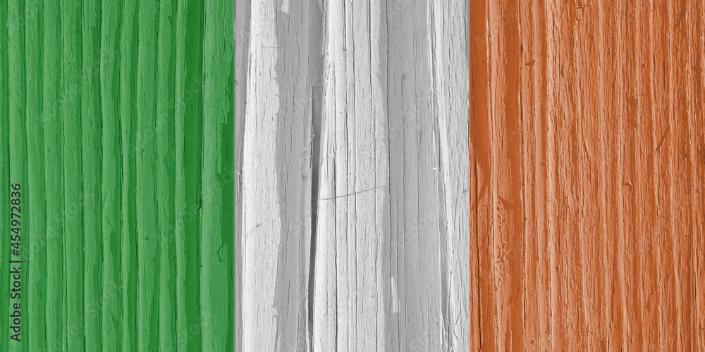The flag of Ireland on dry wooden surface, cracked with age. Light pale ...