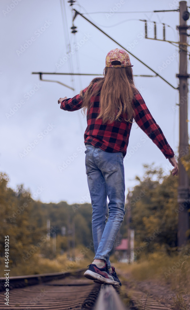 Baby girl on the railway tracks. Girl on the railroad in jeans, cap and ...