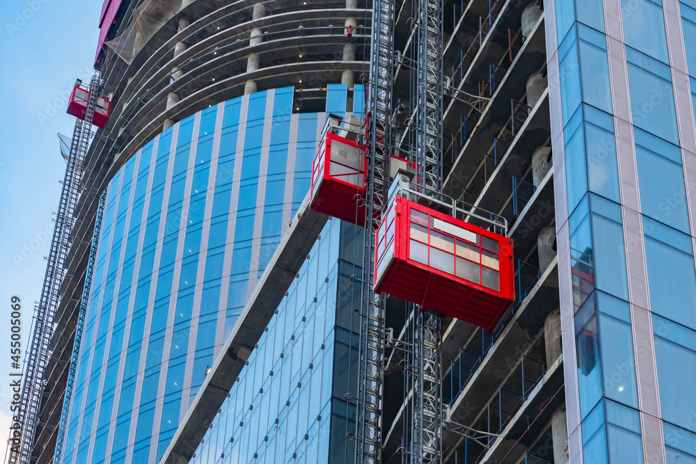 Construction site with elevator lift. Glass skyscraper with elevator ...