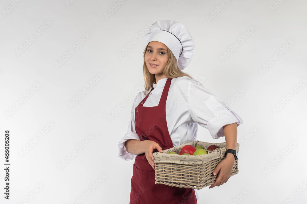 Cook with basket of fruits. Wicker basket in hands of woman chef. Girl ...