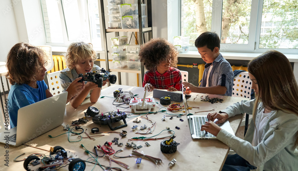 Diverse school children students group building robotic cars using ...